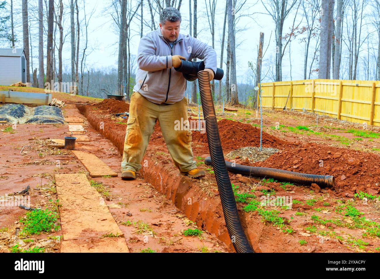 Man is working on installing drainage system in backyard, in freshly ...