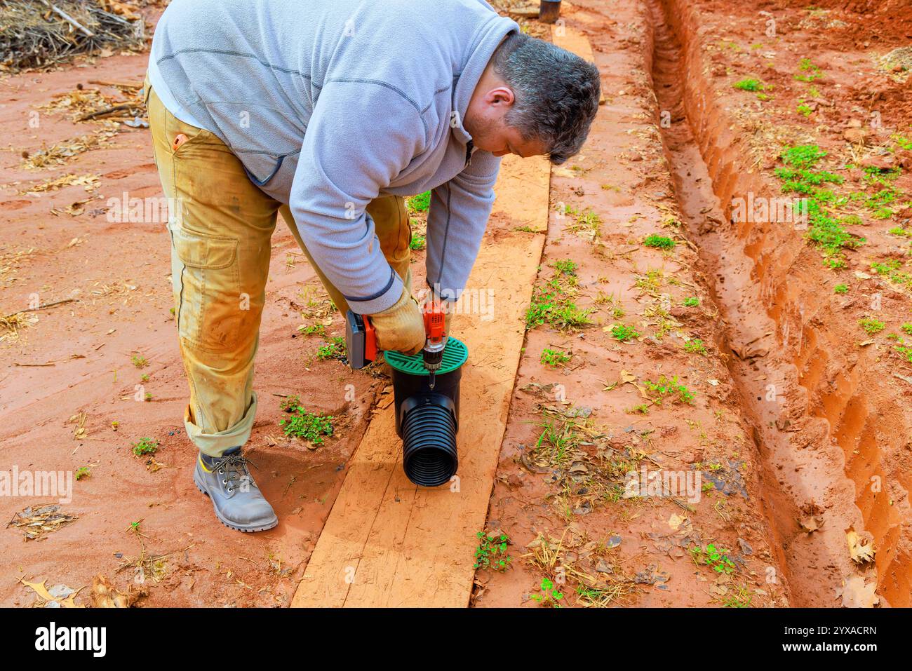 Man is fixing drainage pipe for enhance water flow management in ...