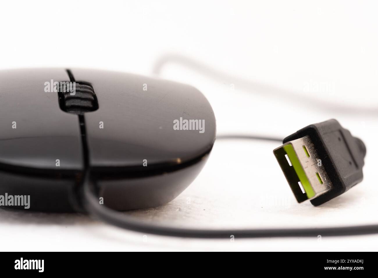A black computer mouse with a green cord attached to it. The mouse is ...