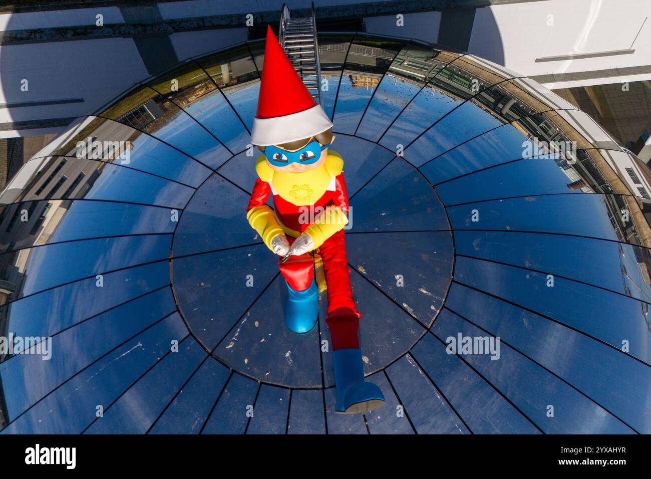 A Christmas Elf on the Shelf, dressed in a super hero costume on top of ...