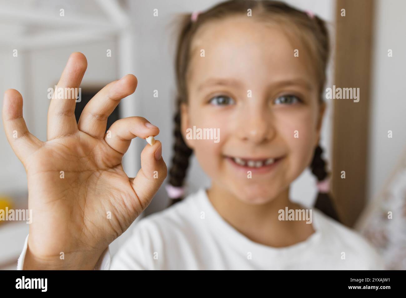Excited young Caucasian girl displaying fallen baby tooth, symbolizing ...