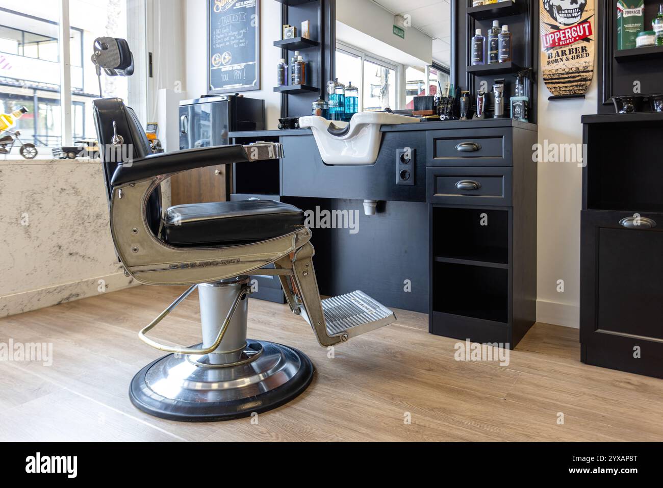 A Belmont barber chair positioned in front of a sleek black workstation ...