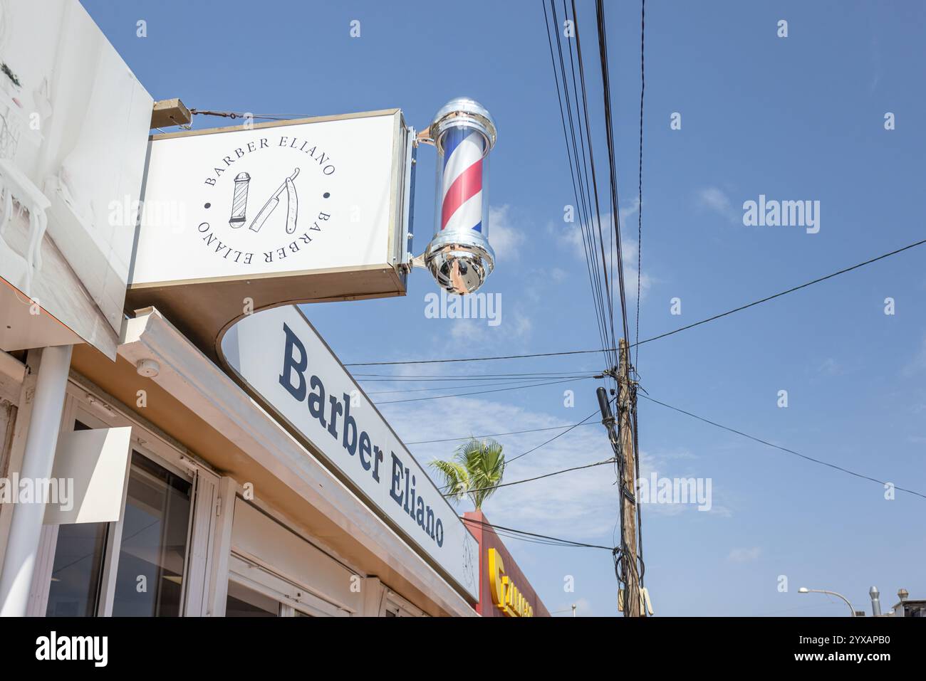 An exterior view of a barber shop featuring a classic red, white, and ...