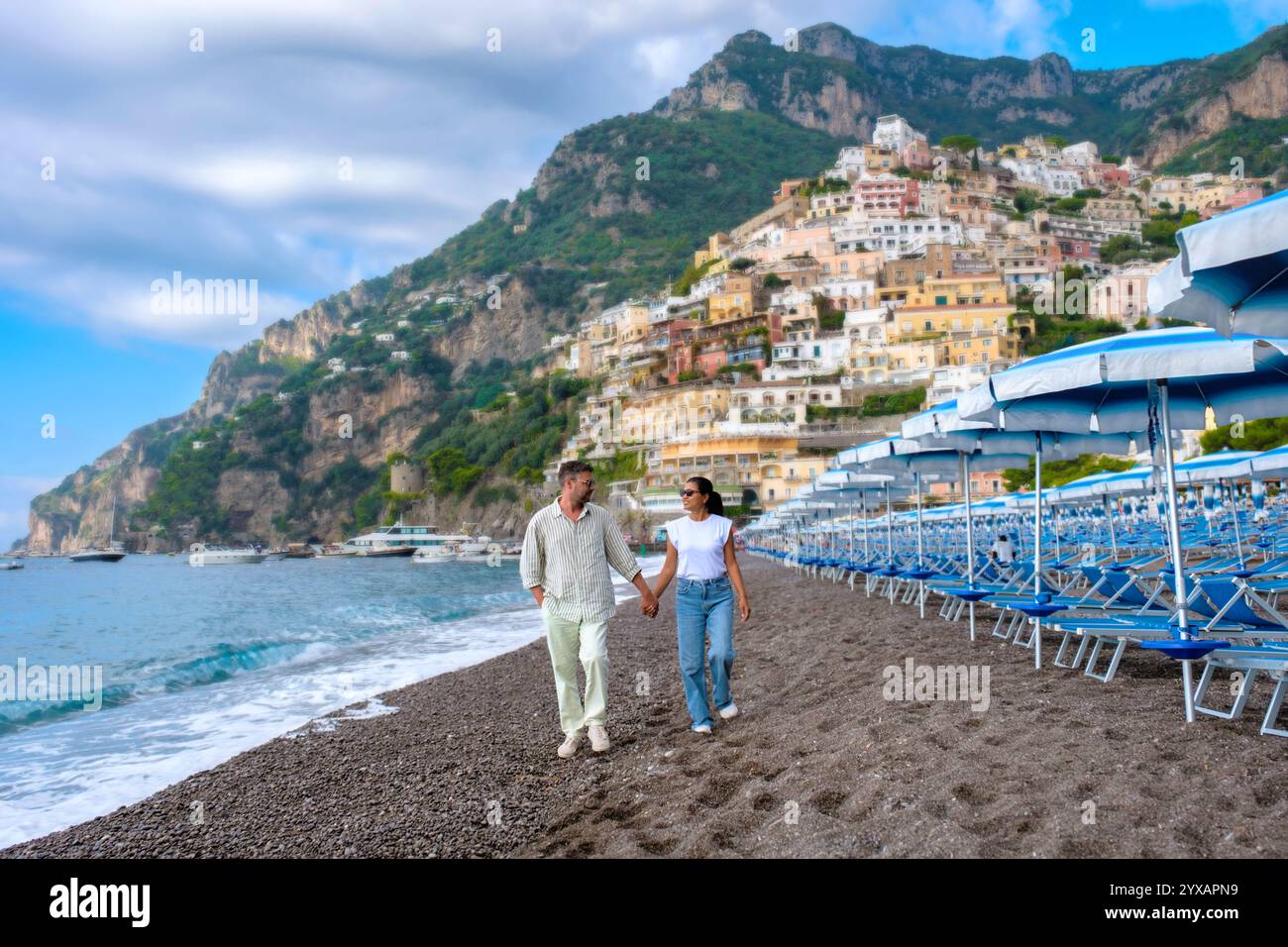 A couple takes a romantic stroll on a picturesque beach in Positano, on the Amalfi Coast in ...