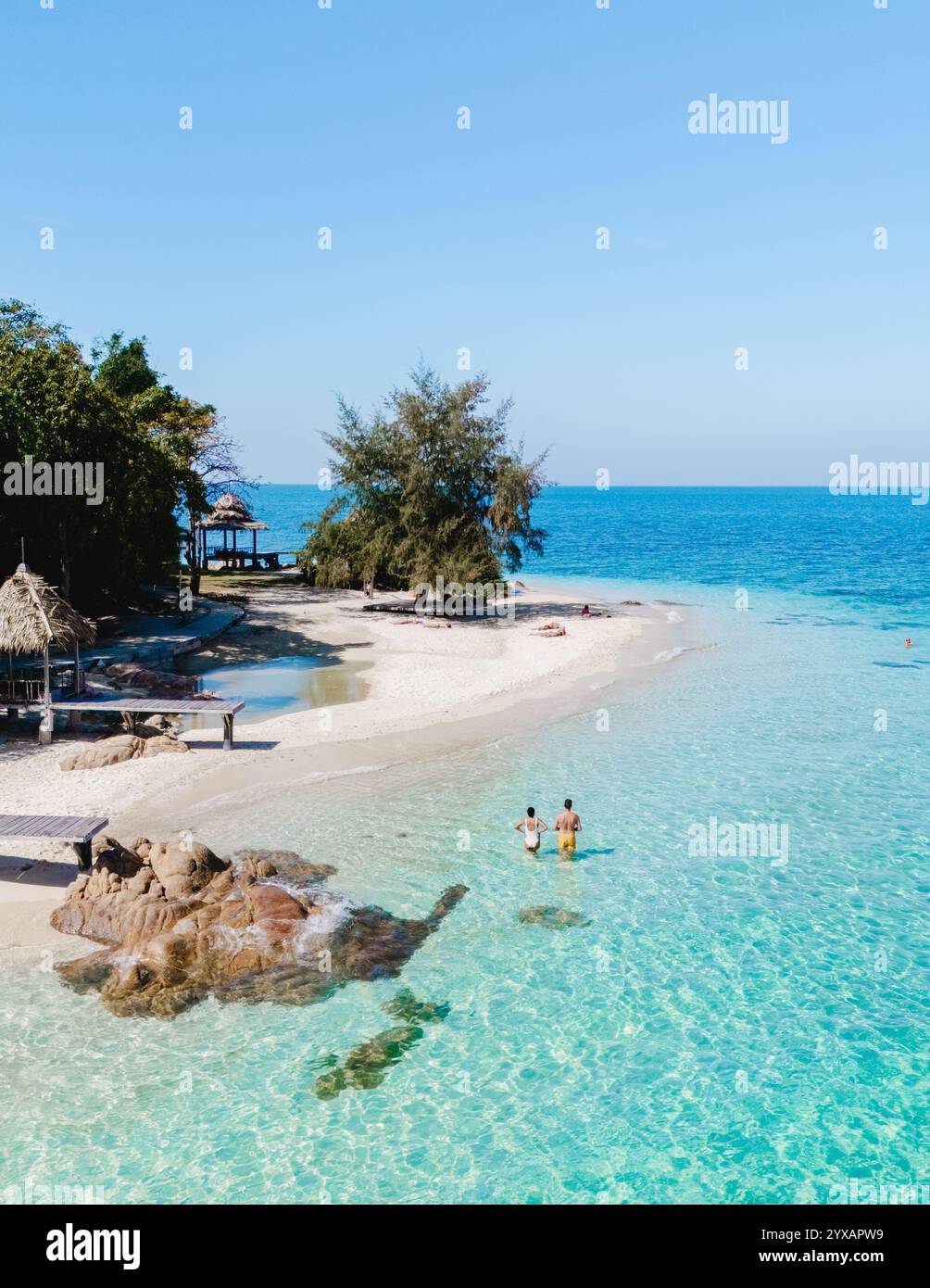 Calm waves lap at the sandy shore as visitors wade through the ...