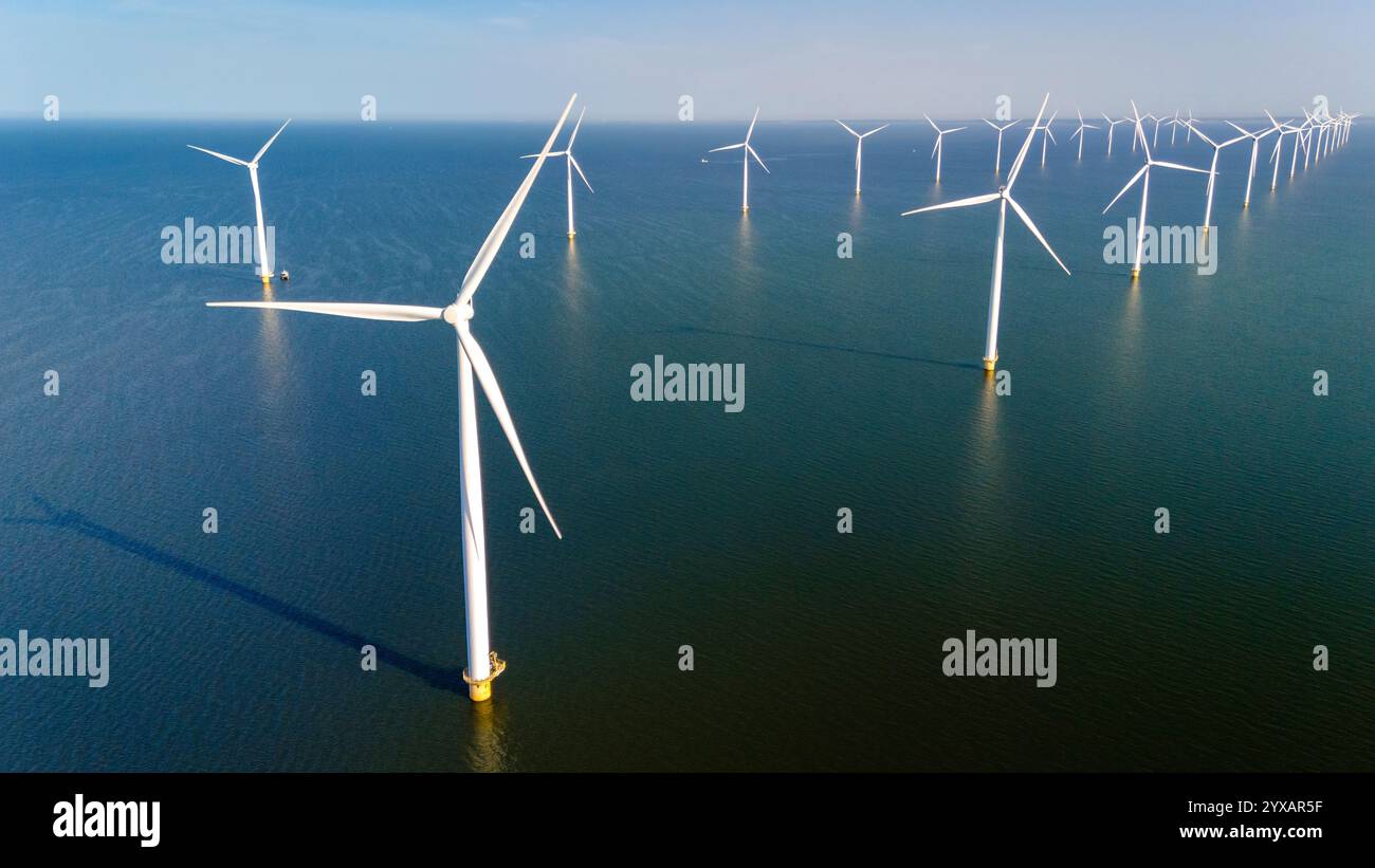row of Windmill turbines generating electric green energy with a blue ...