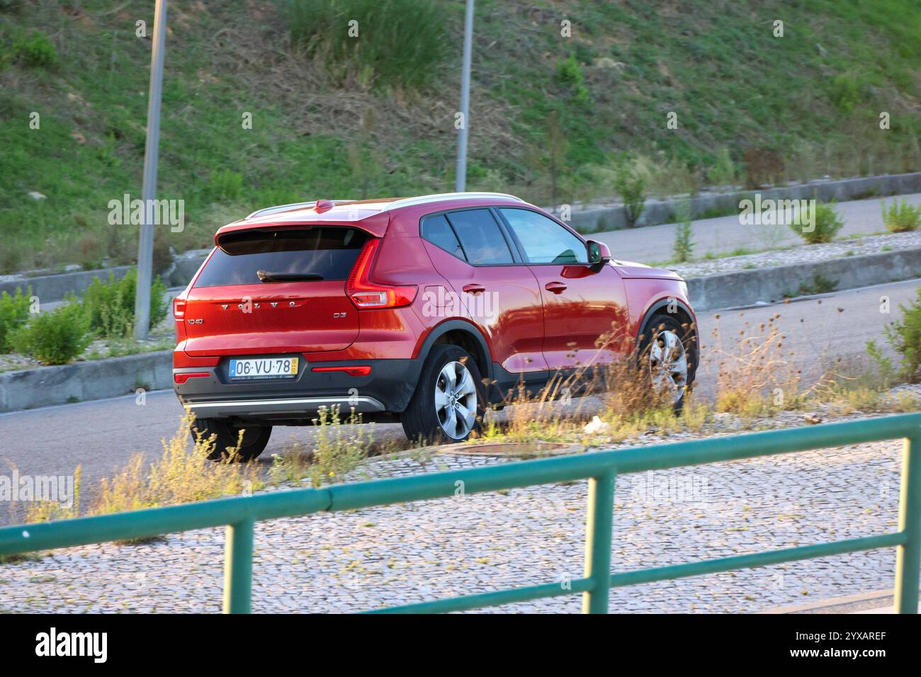 Red volvo xc40 driving on a road next to a green railing Stock Photo ...