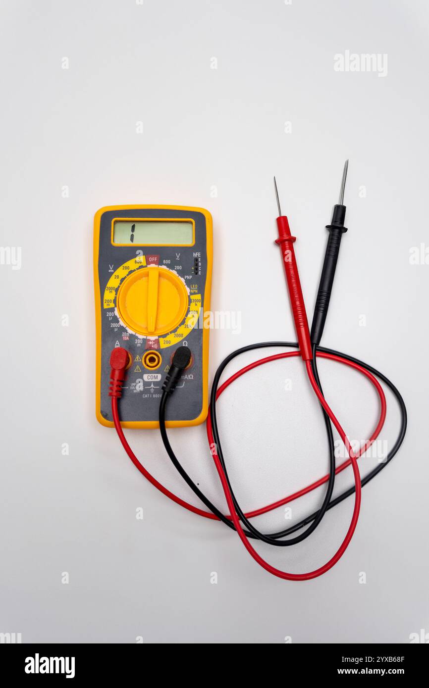 Yellow multimeter showing electrical measurement with probes on white ...