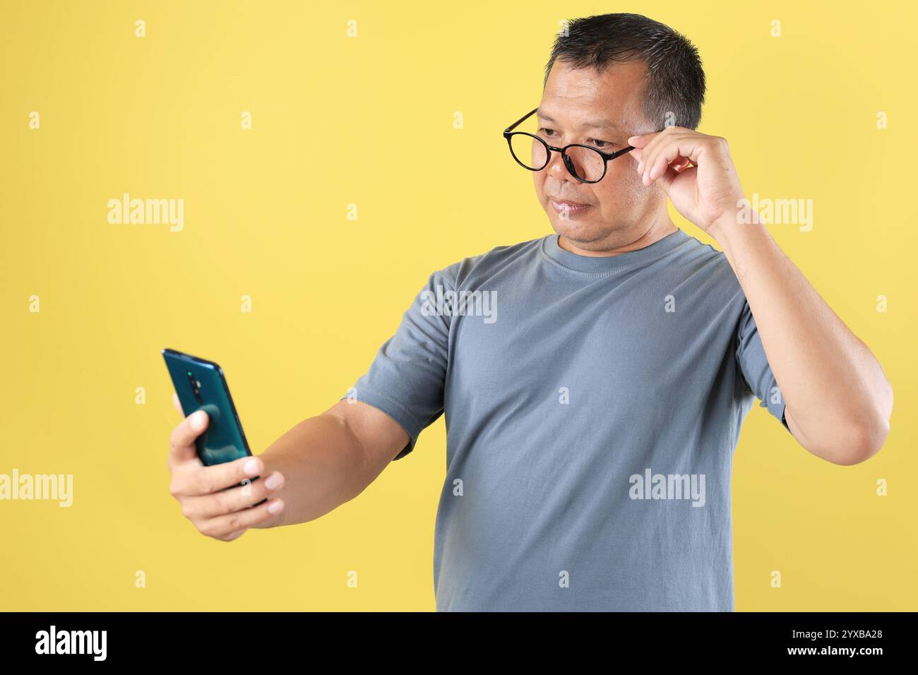 Middle Aged Indonesian Man Squinting at Smart Phone, Senior Asian Man ...