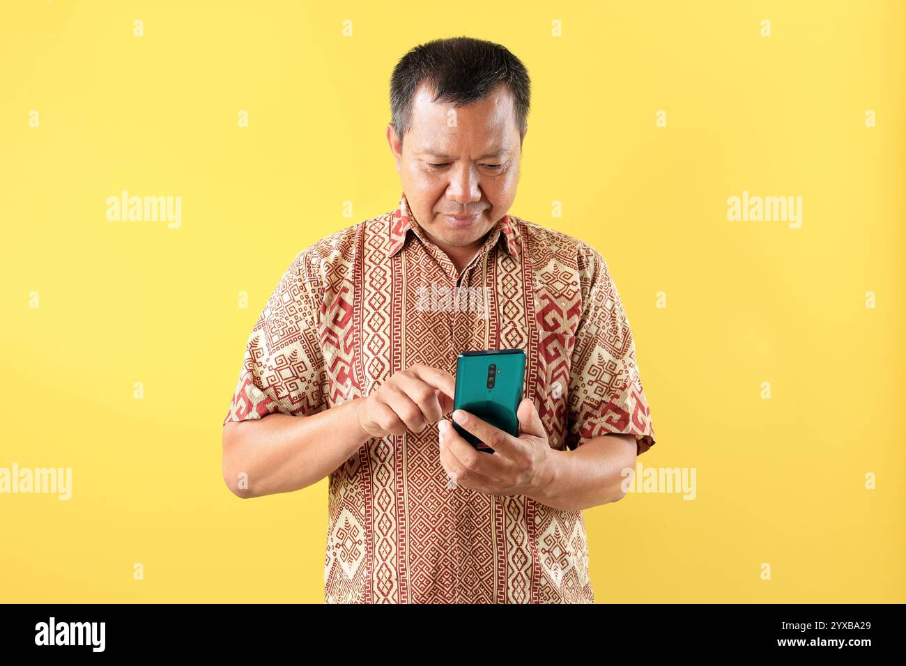 Portrait of Middle Aged Asian Man using Mobile Phone Isolated on Yellow ...