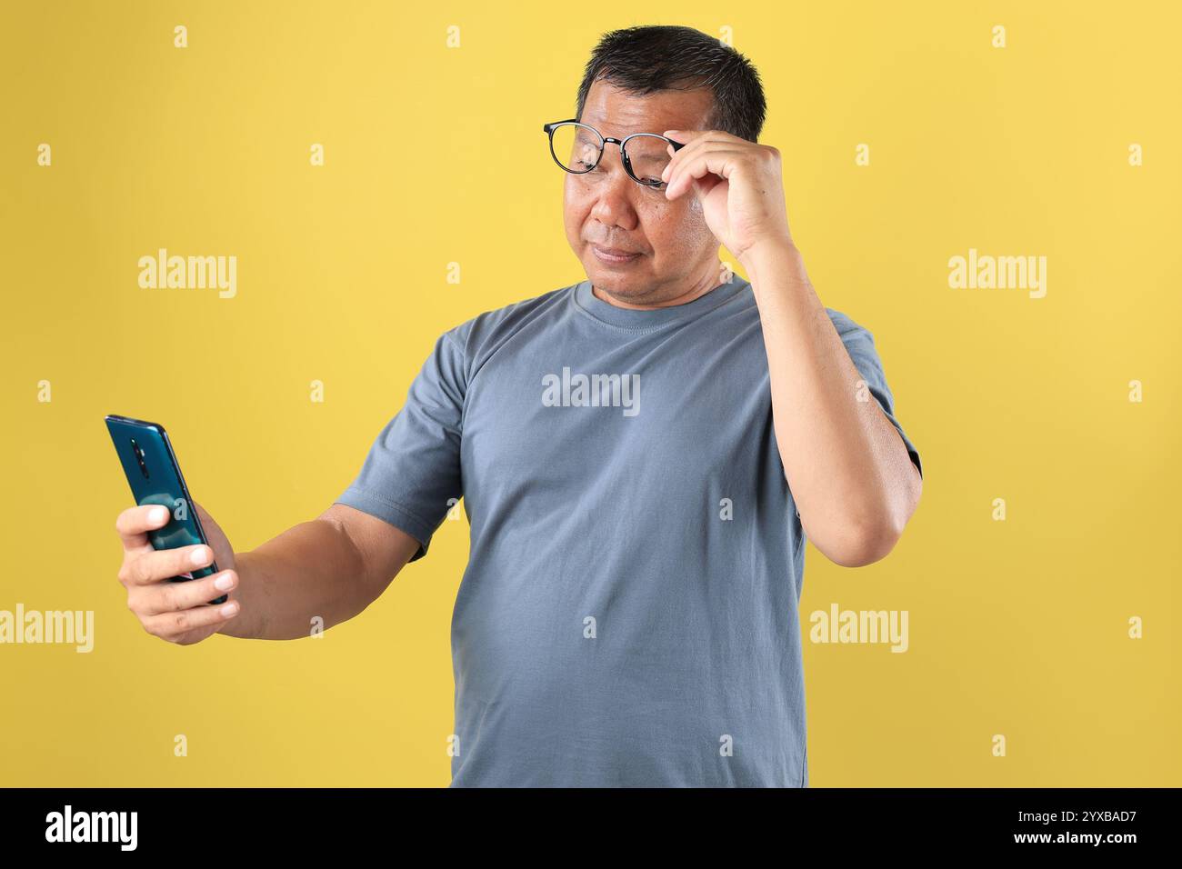 Middle Aged Indonesian Man Squinting at Smart Phone, Senior Asian Man ...