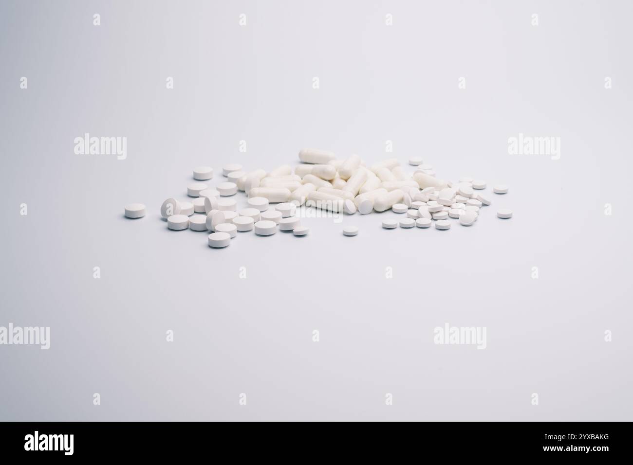 A collection of various white pills and capsules scattered on a clean ...