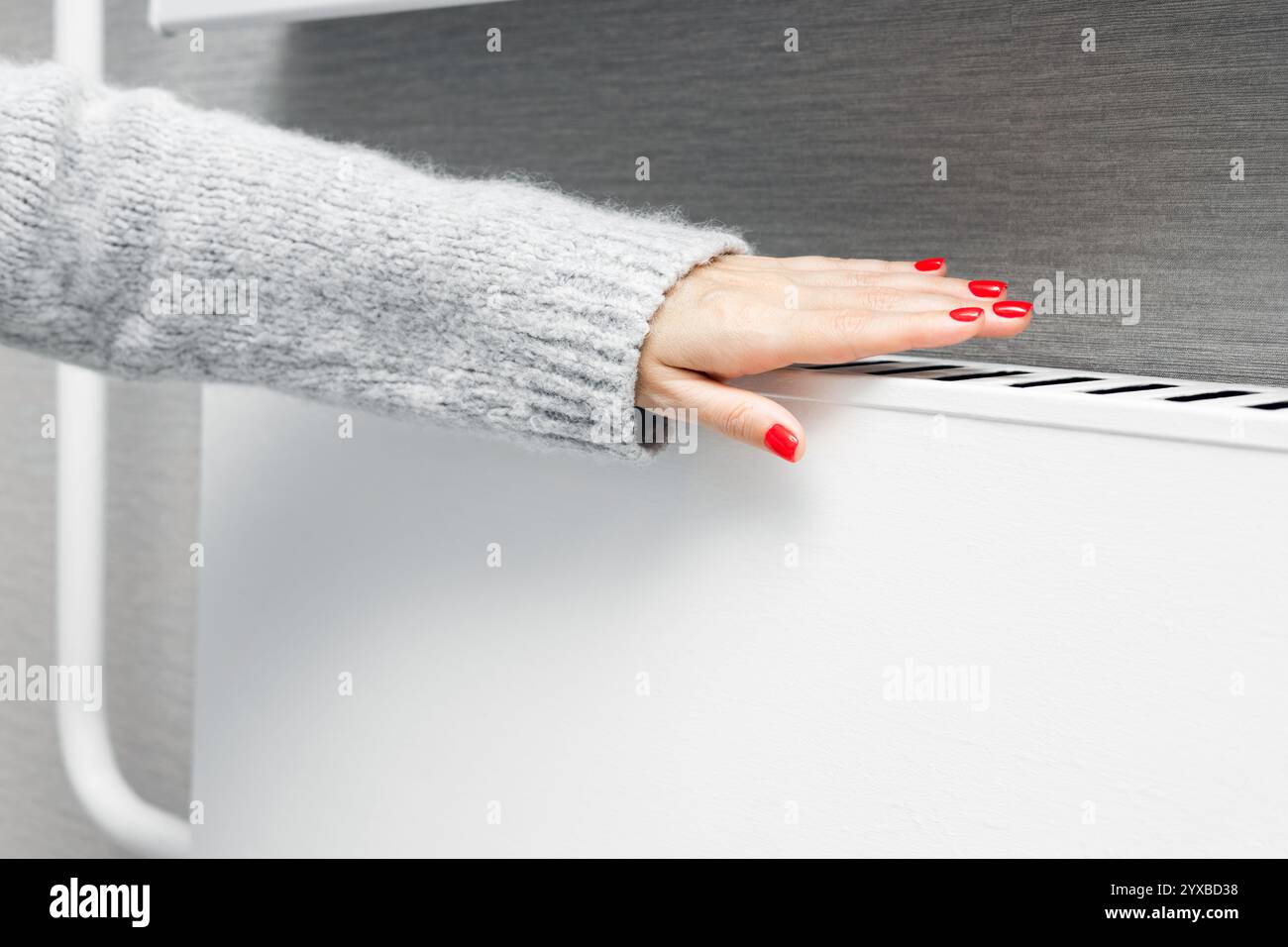A woman checks the temperature of a heating radiator with her hand ...