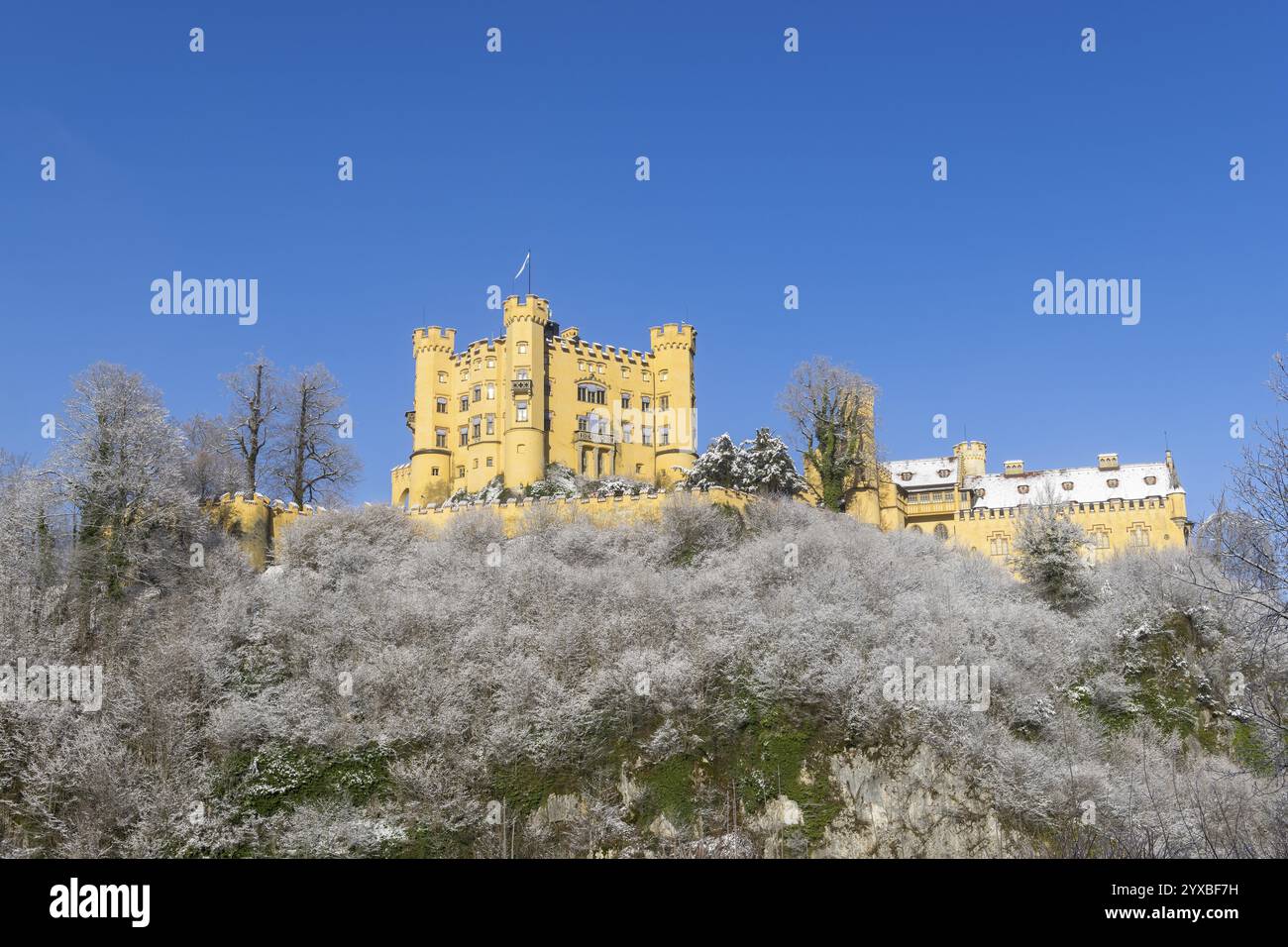 An imposing yellow castle sits on a snow-covered hill in front of an ...