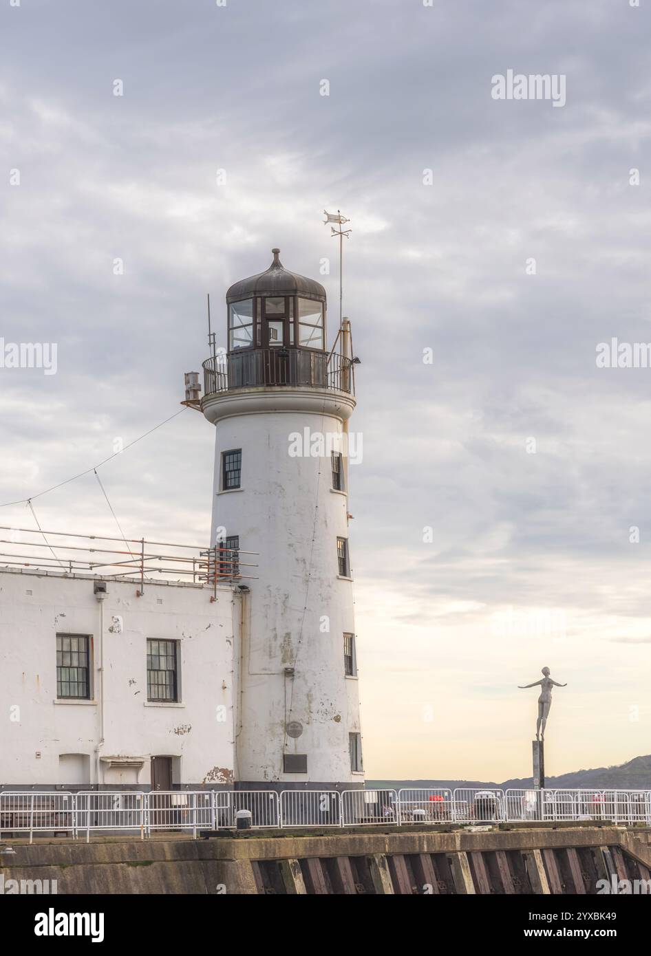 The lighthouse at Scarborough in winter with a memorial figure with ...
