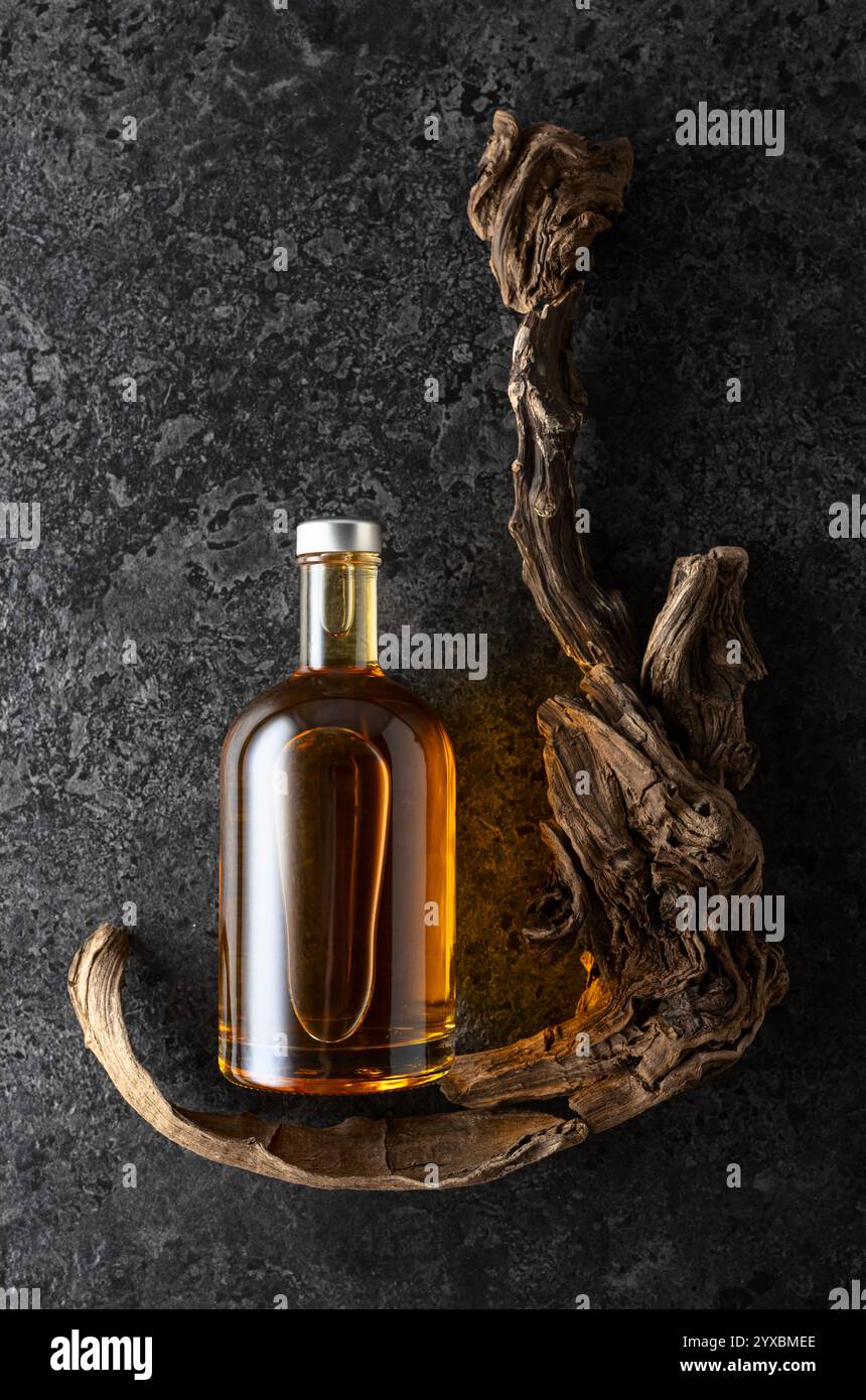 Bottle of whiskey and old snags on a black stone background. Top view ...