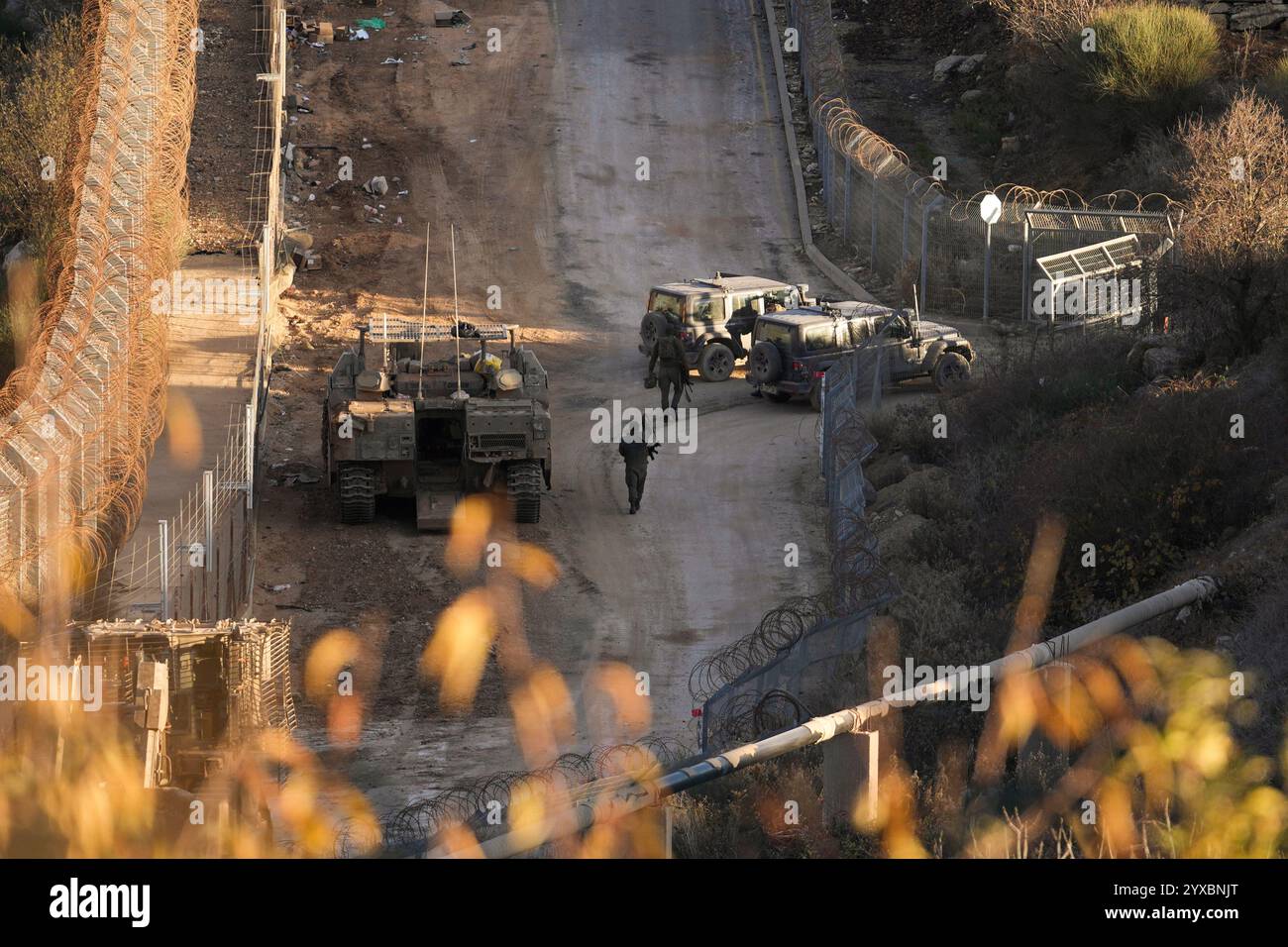 An Israeli soldier walks next to armored vehicles parked near the so ...