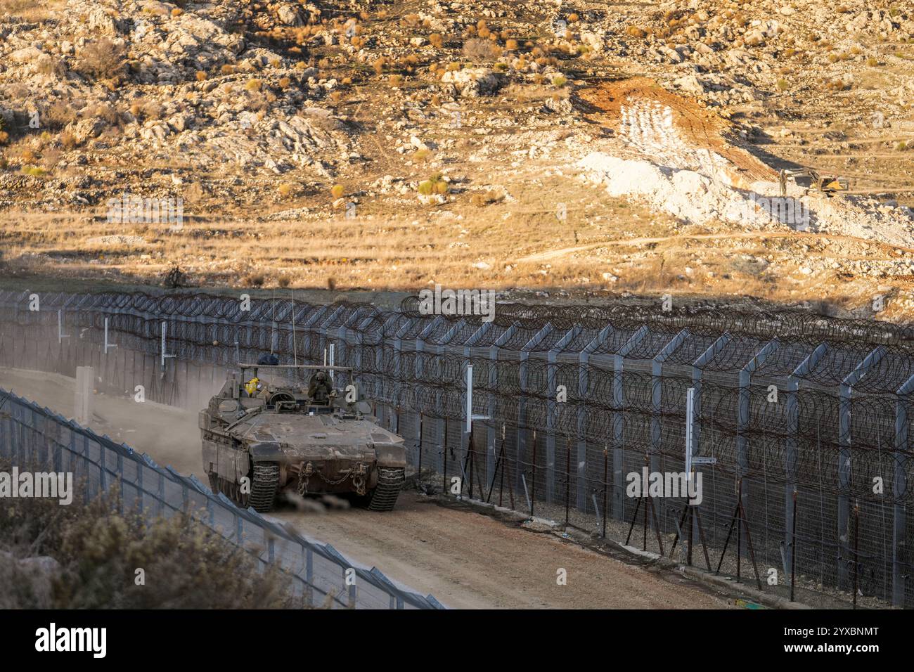 An Israeli armoured vehicle maneuvers along the security fence near the ...