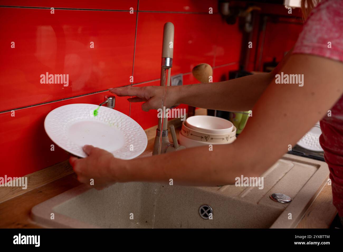A woman washes plates in her modern kitchen, enjoying the atmosphere ...