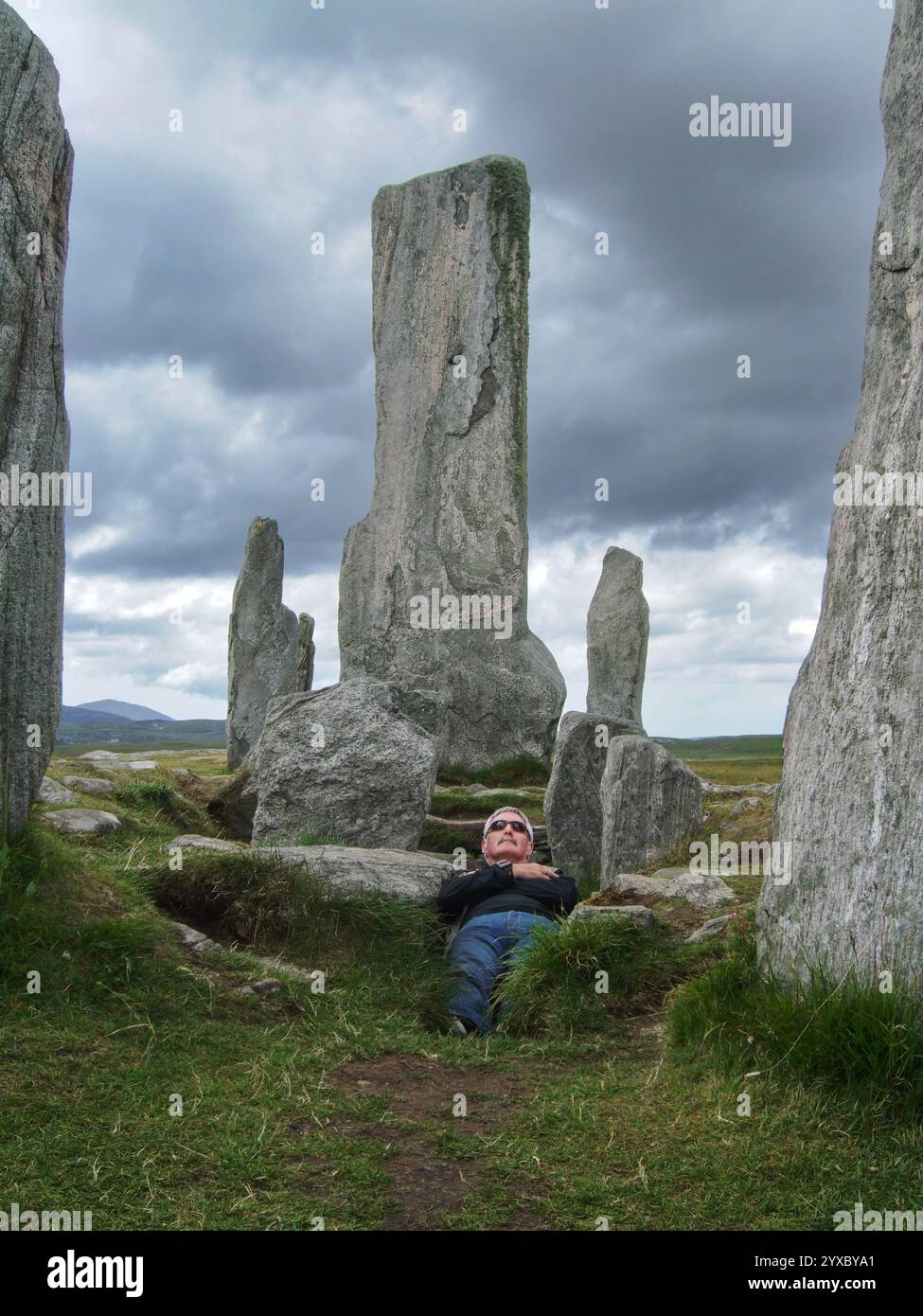 Man lying down pretending to be in a grave pit at Callanish standing ...