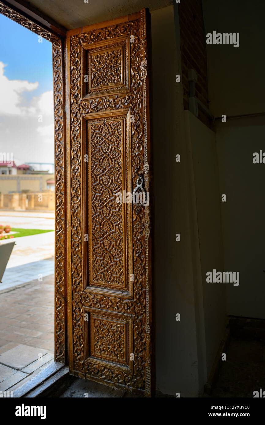An ancient carved wooden door is open to the courtyard at the Registan ...