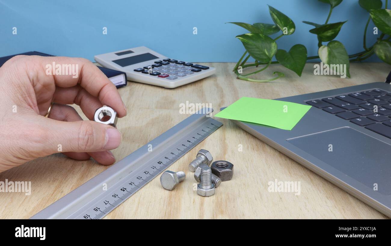 Man with hand demonstrating a bolt, on the desk of an engineering ...