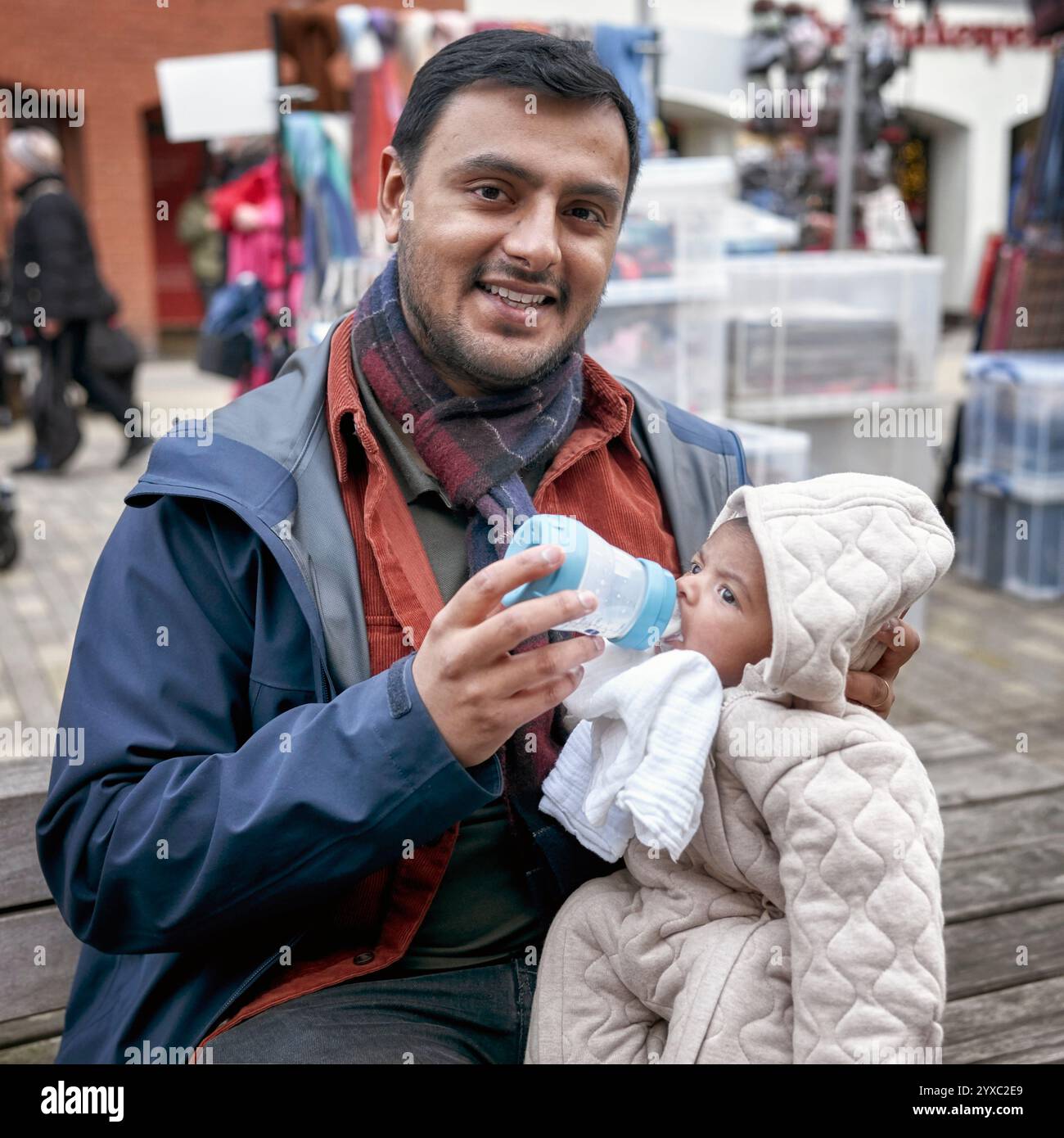 Asian father feeding baby milk from a bottle. Man feeding baby a drink ...