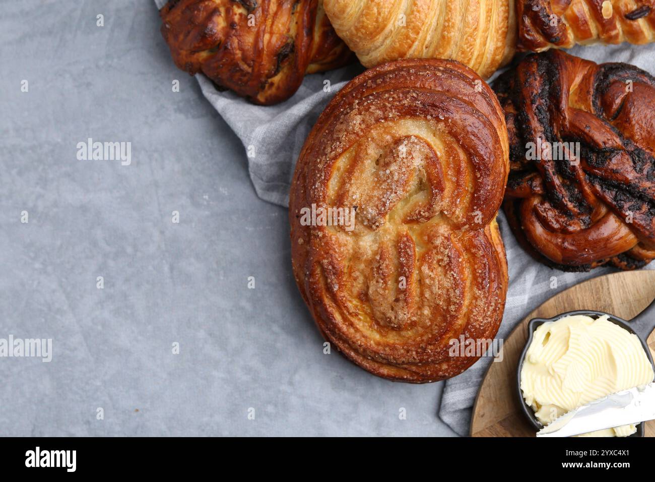 Different delicious pastries and butter on grey table, top view. Space ...