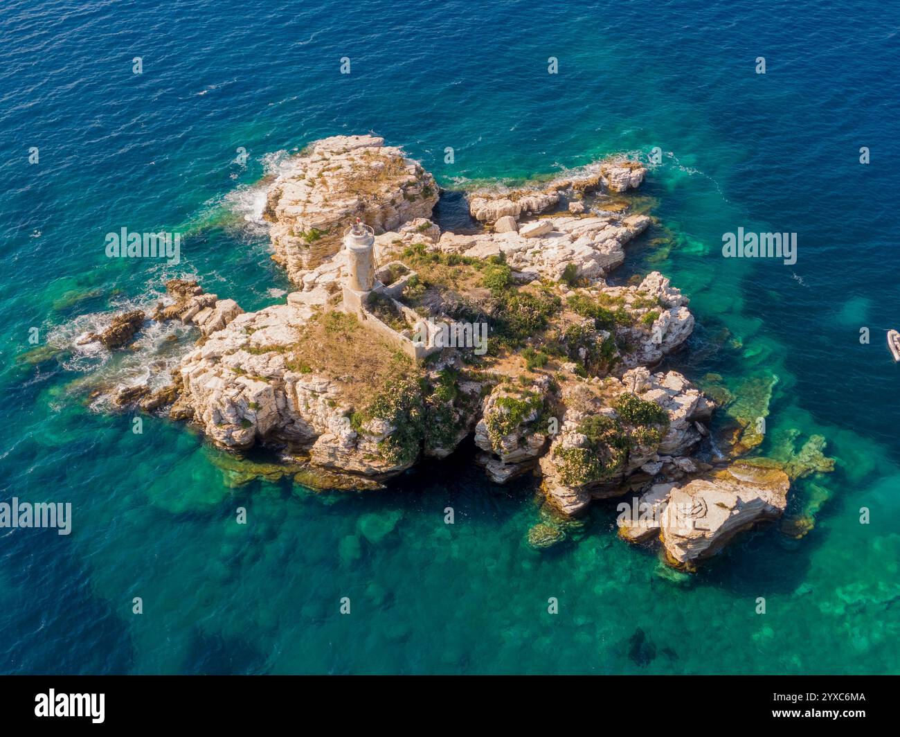 Aerial view of a rocky island with an old lighthouse in the turquoise ...