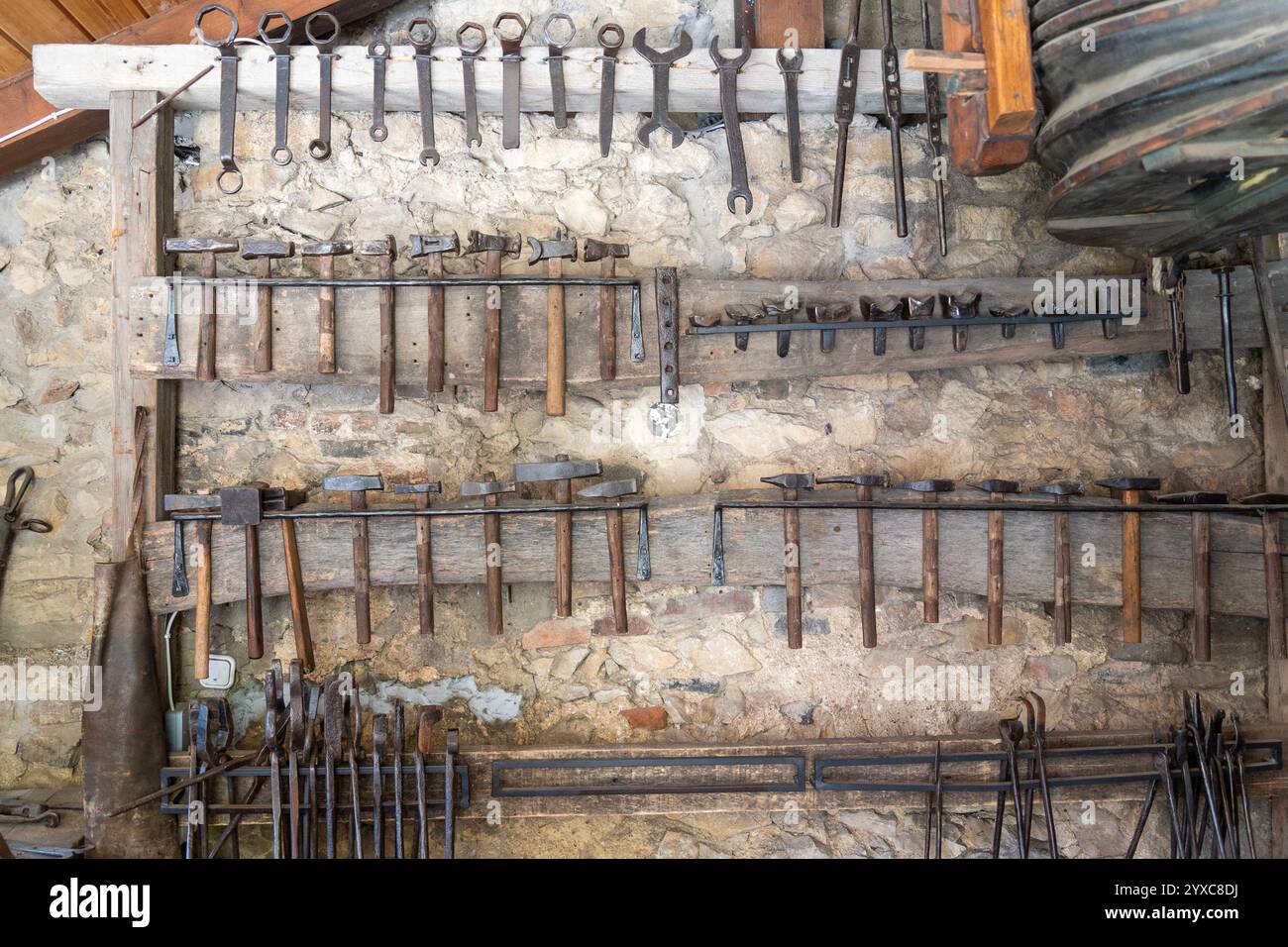 Traditional blacksmith tools on a rustic stone wall in a blacksmith ...