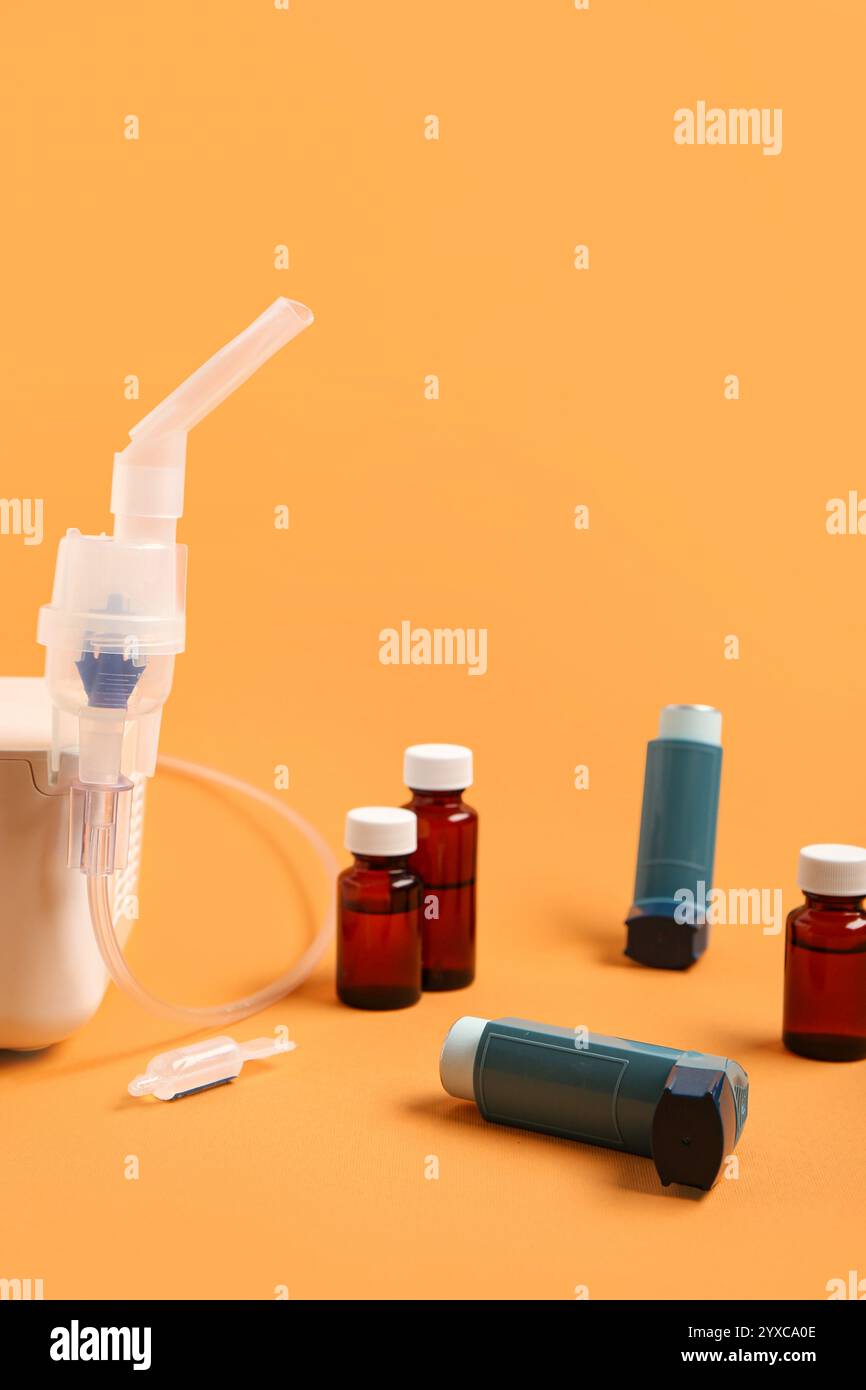 Modern inhalers and bottles of medicines on orange background Stock ...