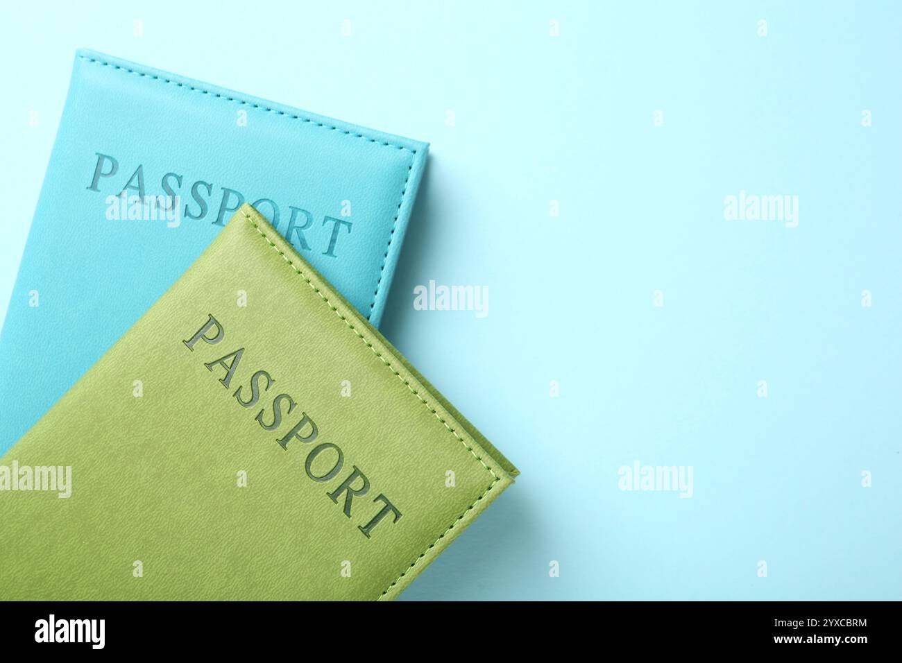 Passports in color covers on light blue background, top view. Space for ...
