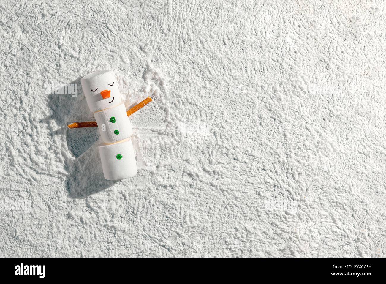 Funny marshmallow snowman lying on snow, creating a snow angel with ...