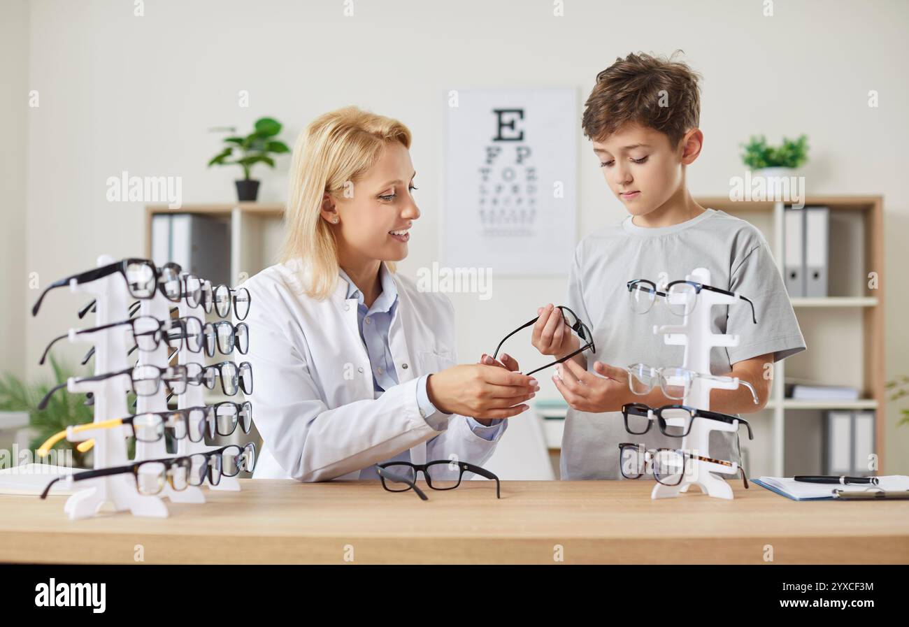 Young optician doctor helping child boy patient to choose new glasses ...