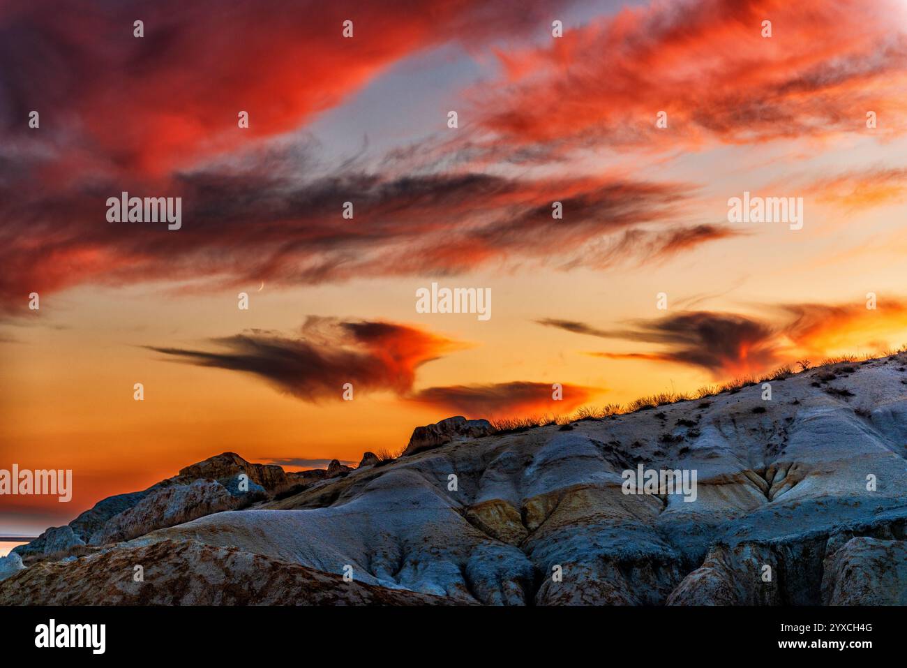 Evening landscape with bright orange clouds and multi-colored clay soil ...