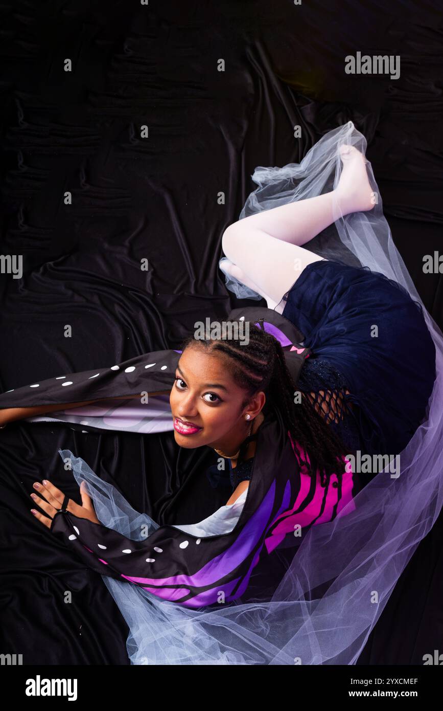 Teenage brunette girl in fetal position dressed in butterfly wings ...