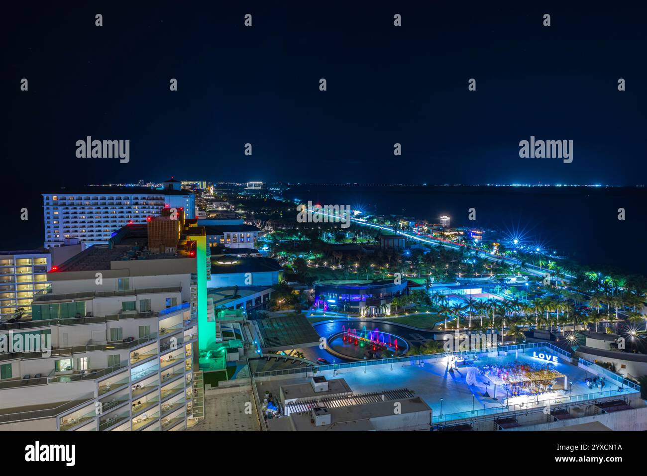 Night view of illuminated coastal resort with modern hotels, palm-lined ...