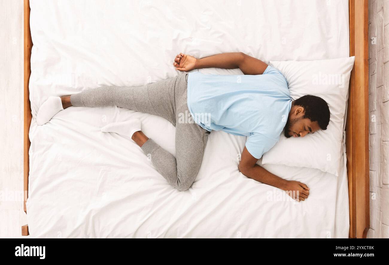 Young african-american man sleeping in bed top view Stock Photo - Alamy