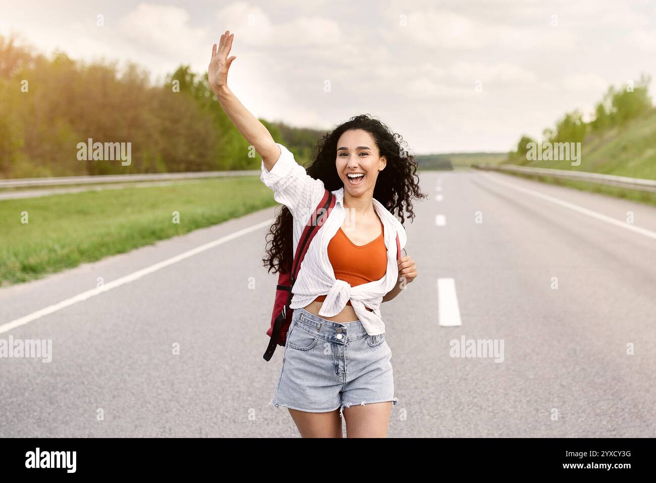 Summertime adventure. Cheerful young woman with rucksack walking along ...