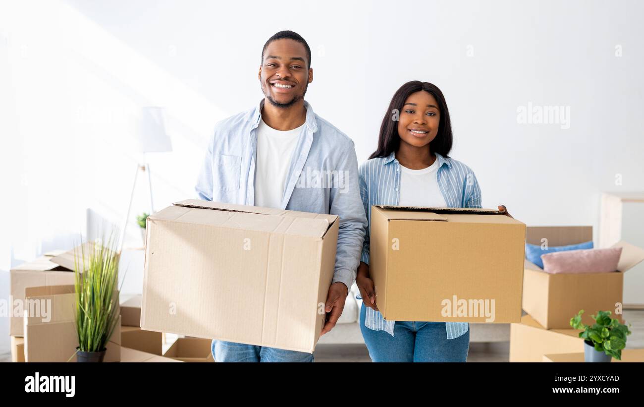 Relocation concept. Happy african american couple carrying cardboard ...