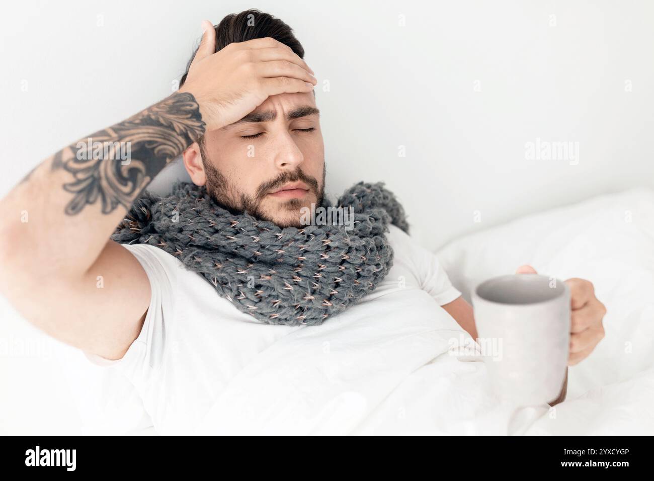 Feeling bad. Sick guy having fever, drinking hot healing tea and ...