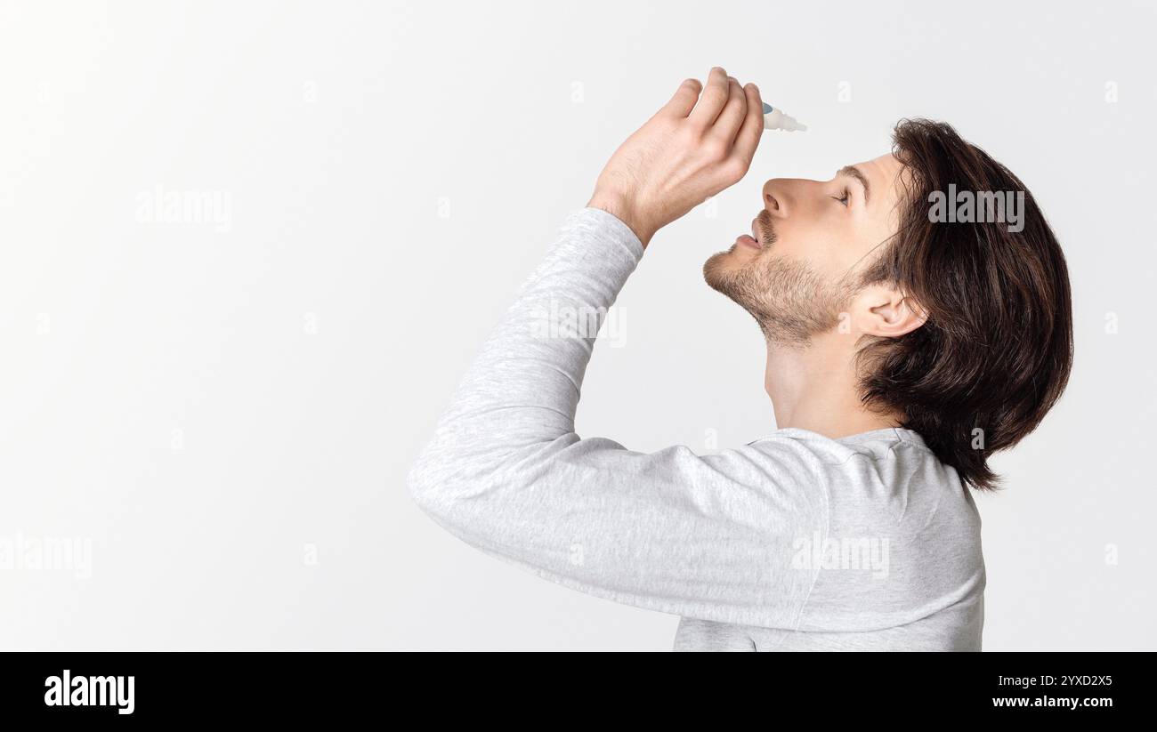 Dry in eyes. Guy dripping eye drops Stock Photo - Alamy