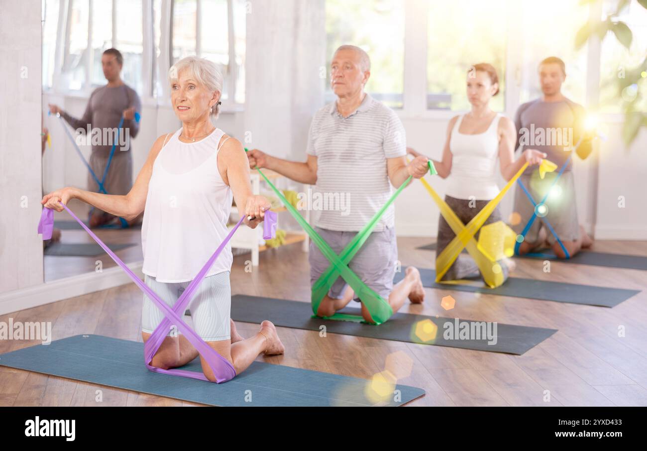 Elderly woman performs exercises with elastic band during Pilates ...
