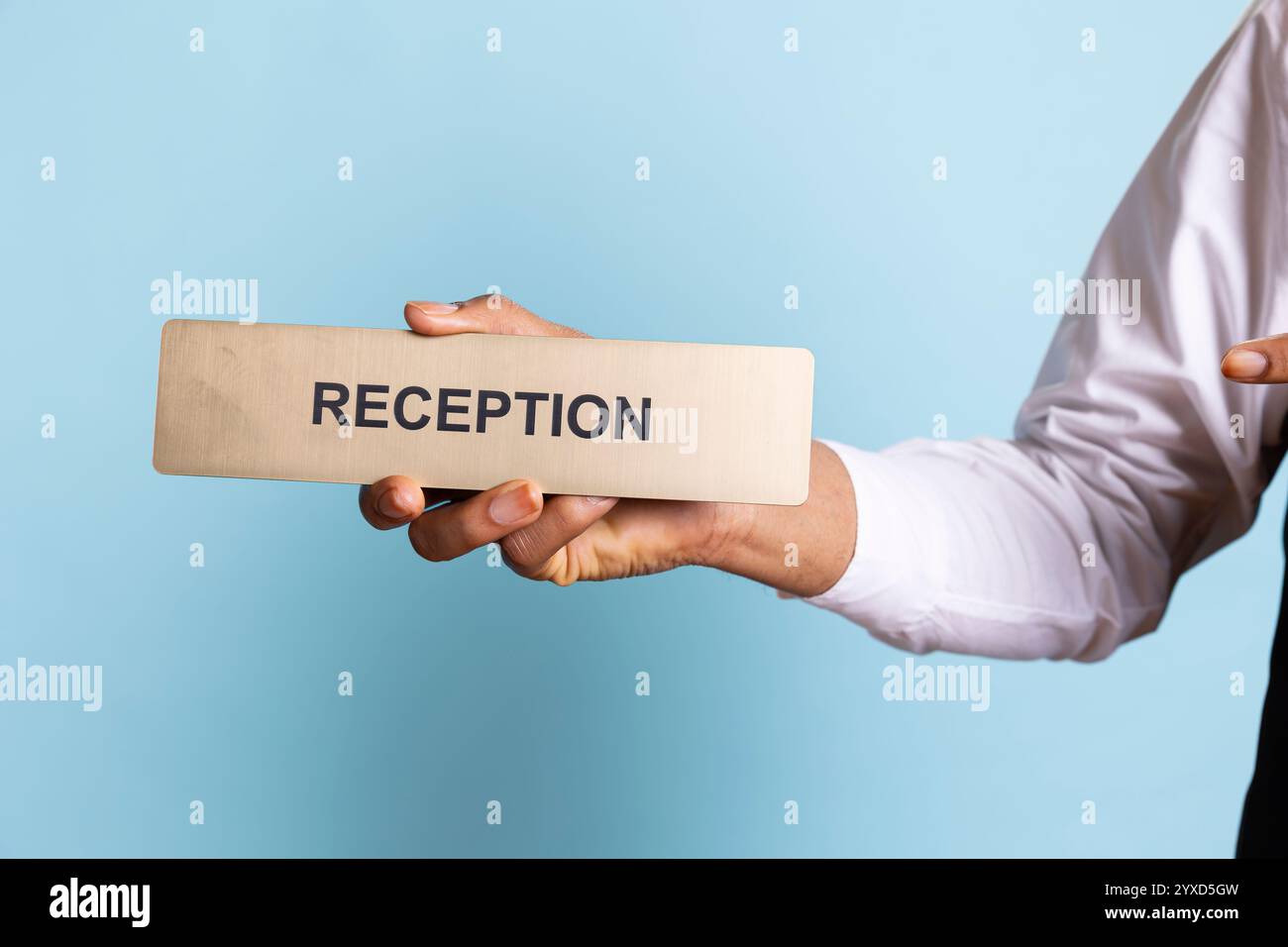 Young bellhop pointing at an indicator for the reception area front ...