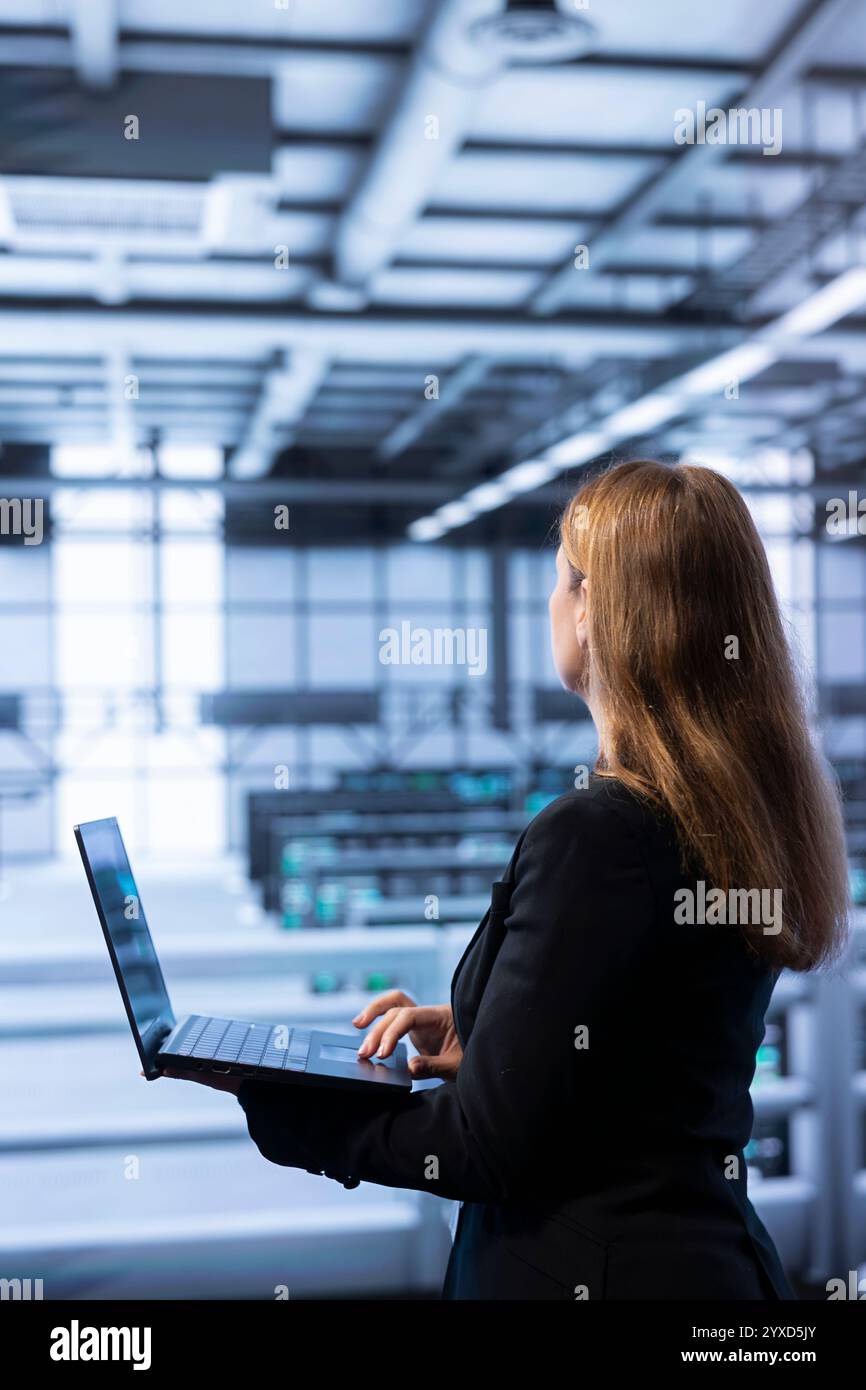 Software developer walking between server rows in data center, doing yearly infrastructure ...