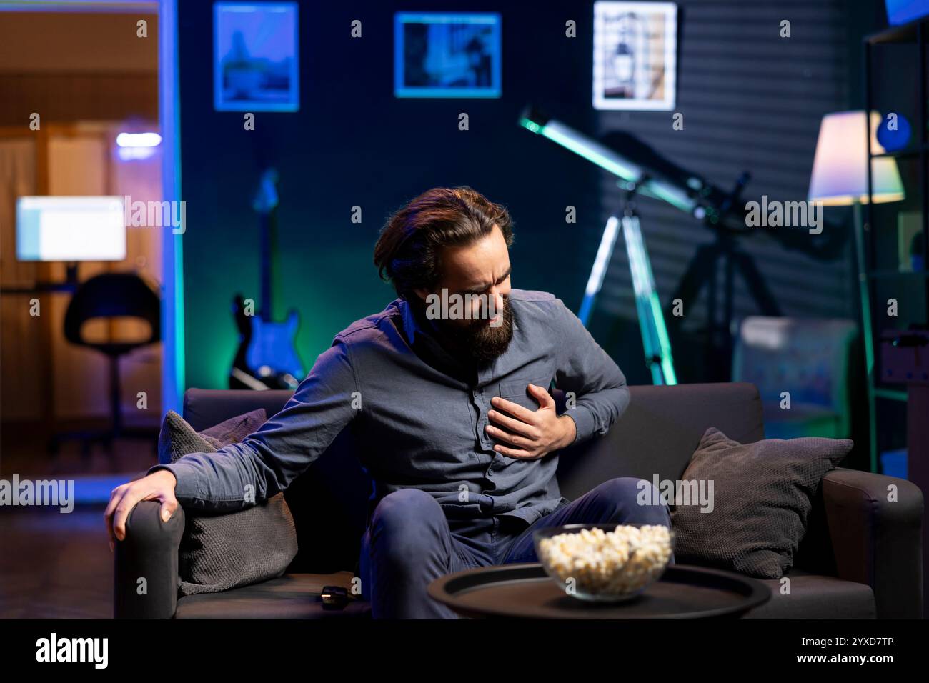 Sedentary man at home feeling terrible pain in chest while watching TV ...