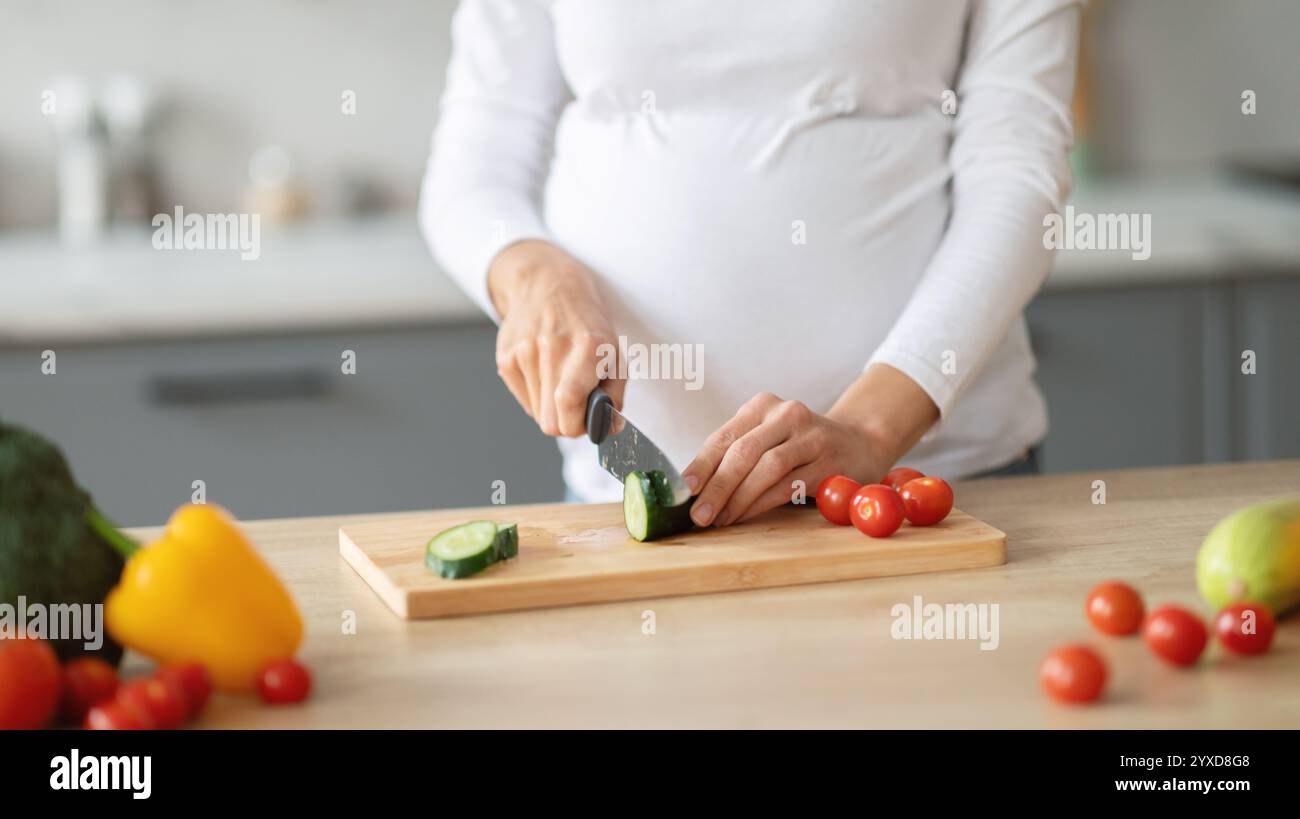 Pregnant woman preparing fresh vegetables in a modern kitchen setting ...
