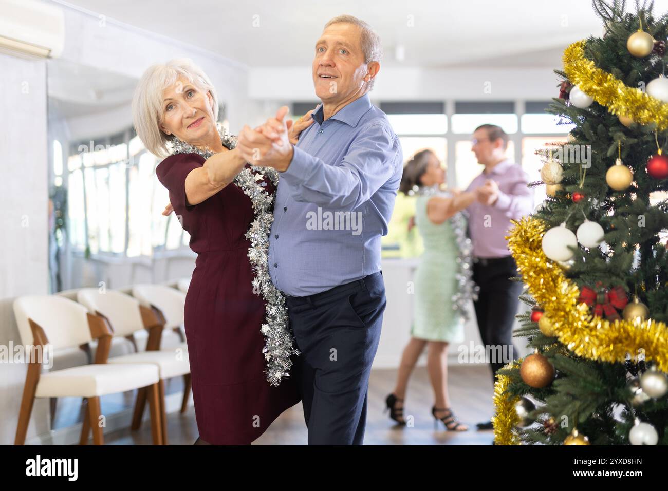 Active mature men and women dancing samba dances in ballroom during ...