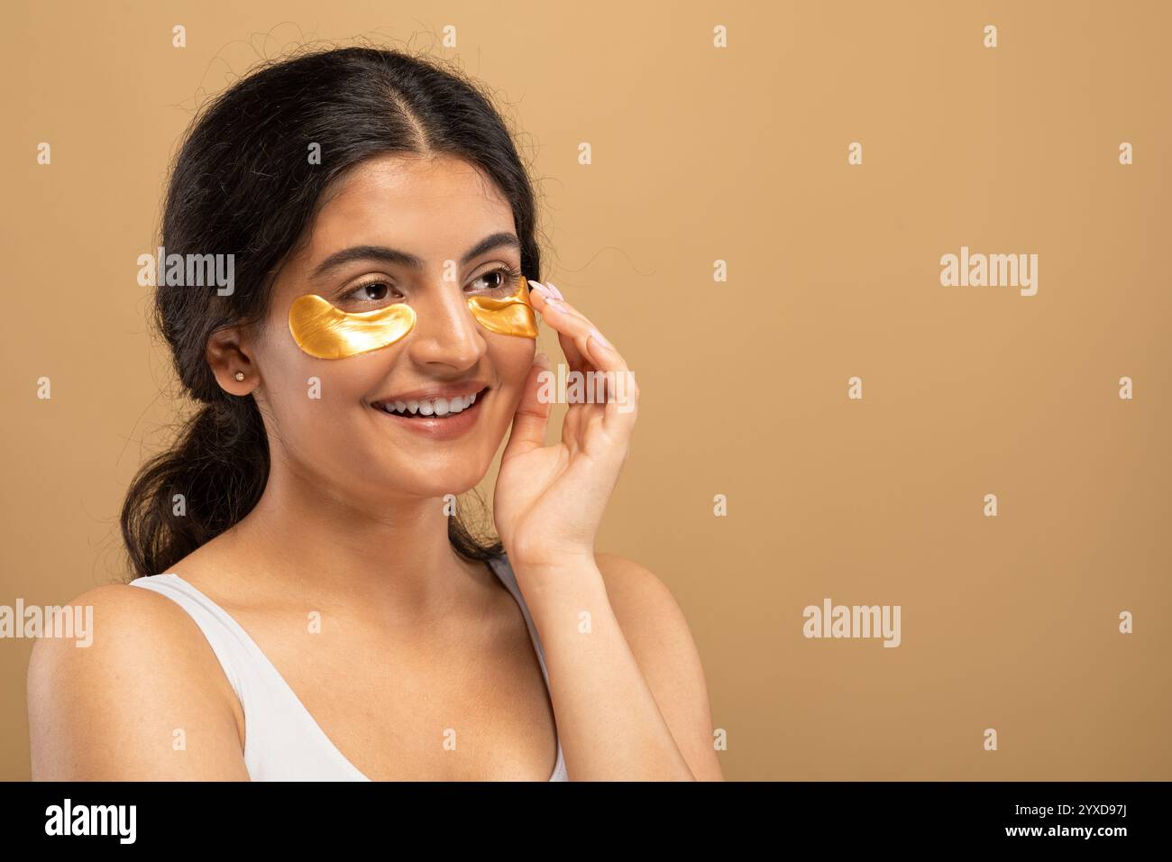 Young Indian woman enjoying skin care pampering with under-eye masks ...