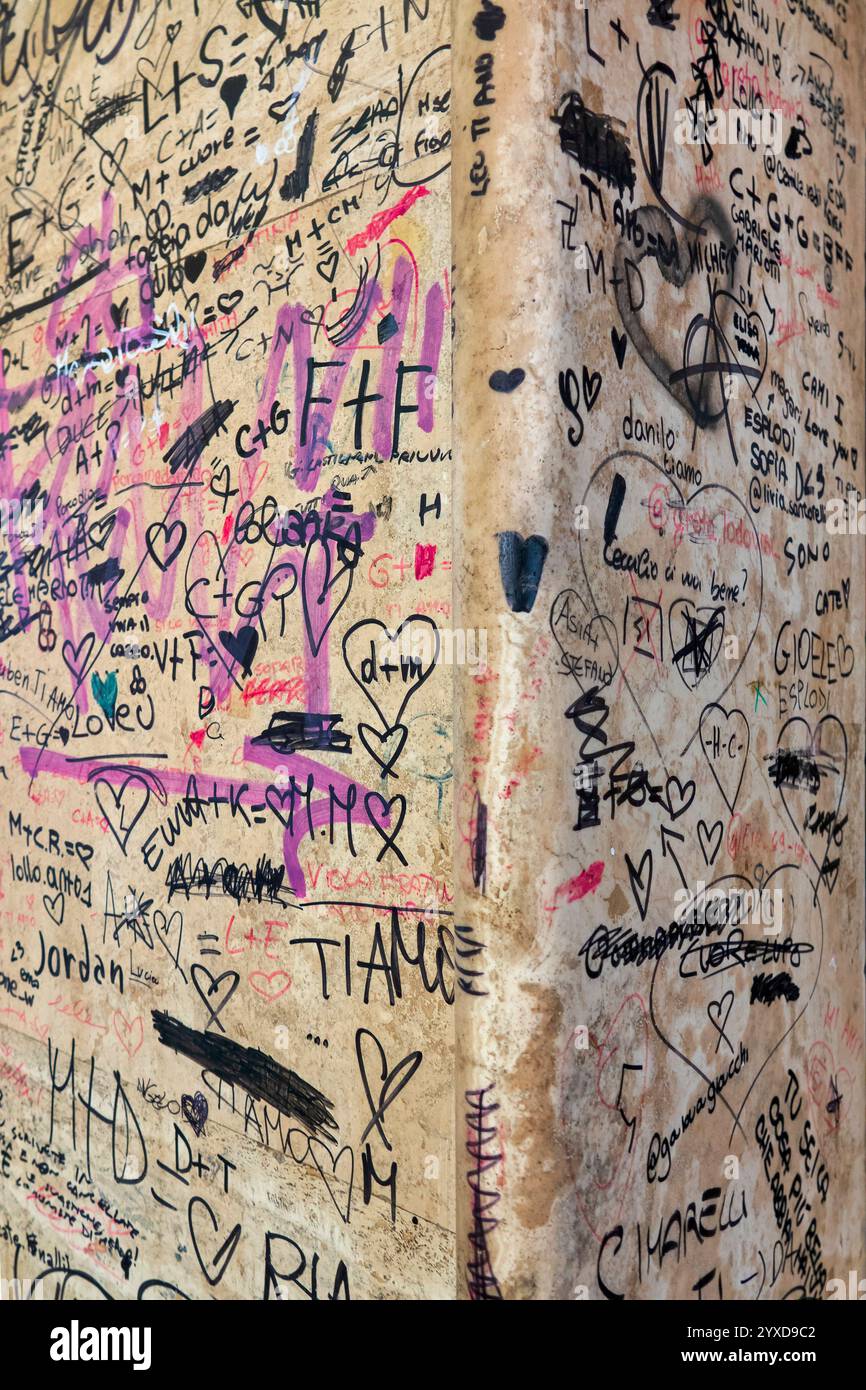 A wall densely covered with graffiti, messages, hearts, and initials ...